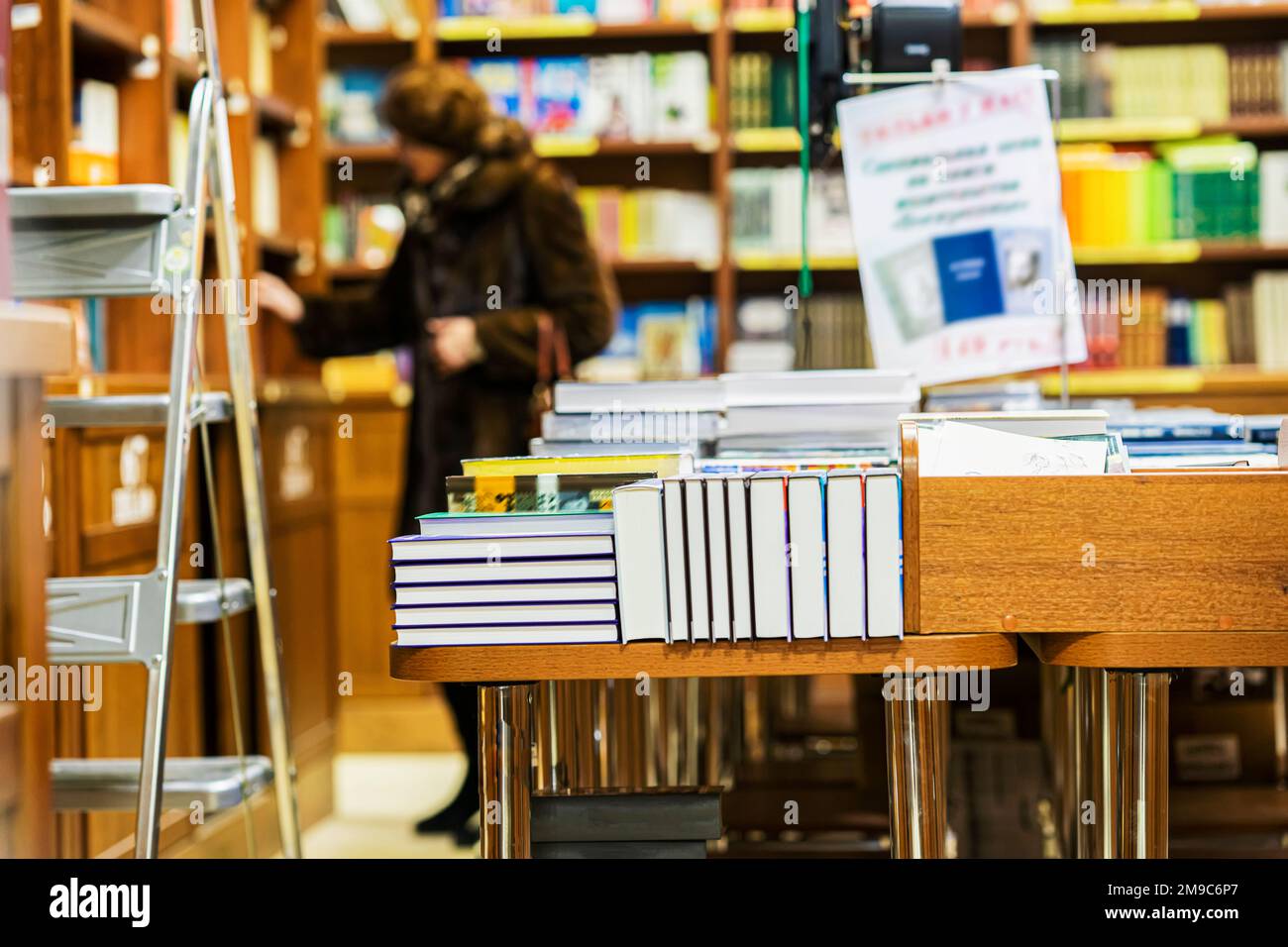 Abstract bookstore, stacks of books on table. Unrecognizable silhouette ...