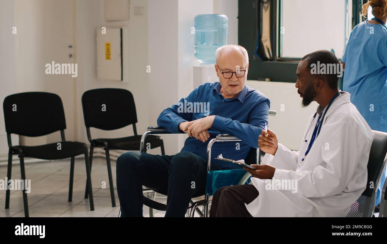 General practitioner doing consultation with old person in wheelchair ...
