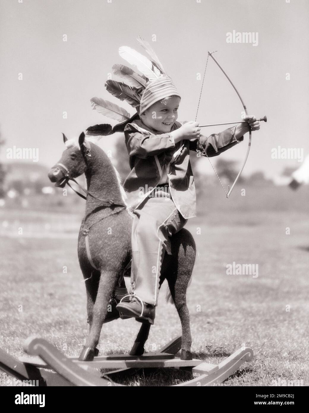 1930s BOY DRESSED AS NATIVE AMERICAN FEATHER BONNET AIMING BOW AND ...