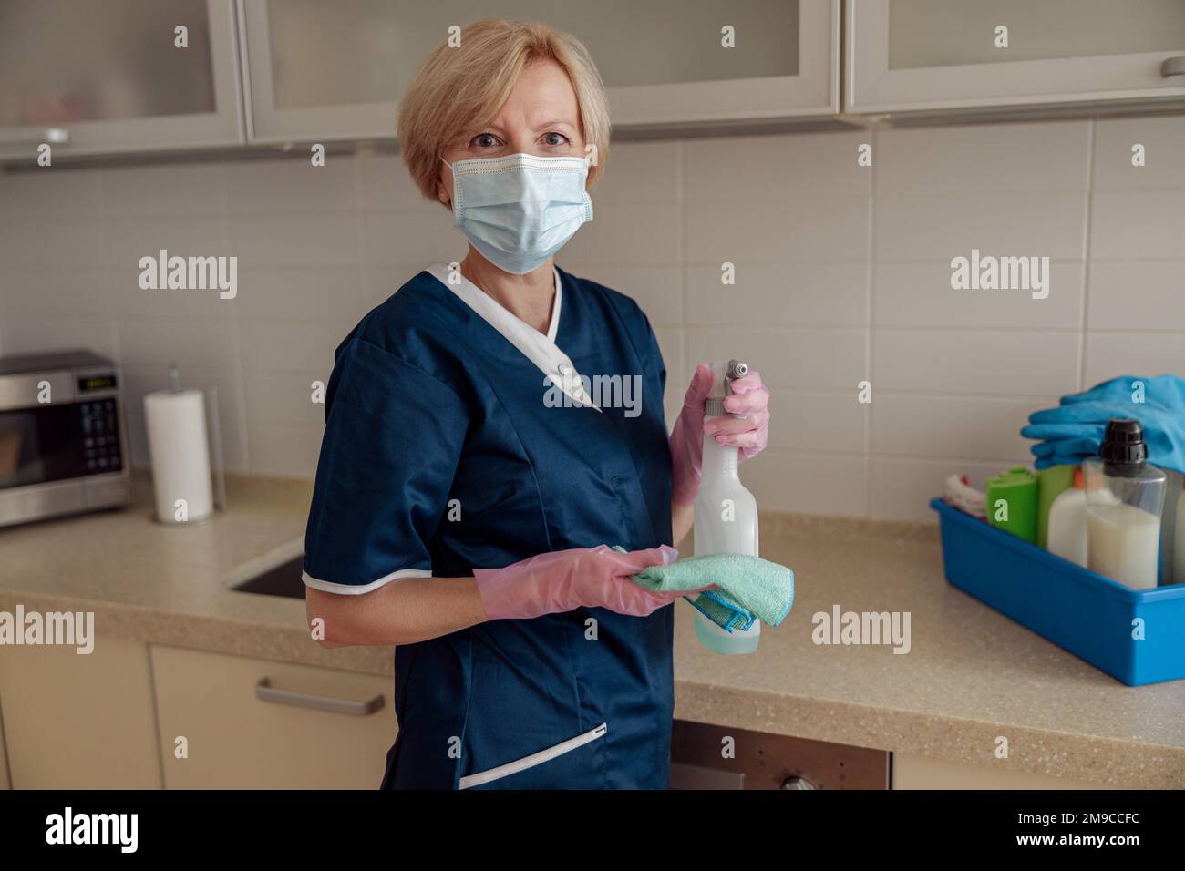 Maid in protective gloves cleans worktop table use rag and effective ...
