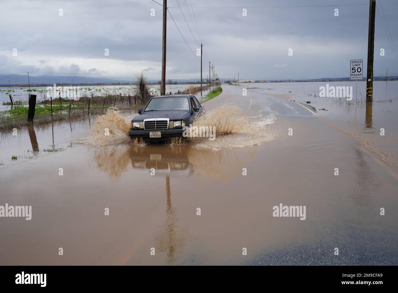 The road flooded in Gilroy and a car drove on the flooding area ...