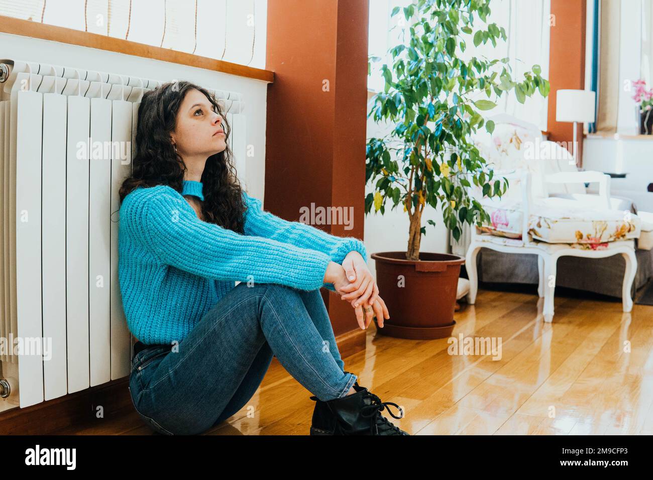 sad woman dressed in blue sitting in the living room of her house Stock ...