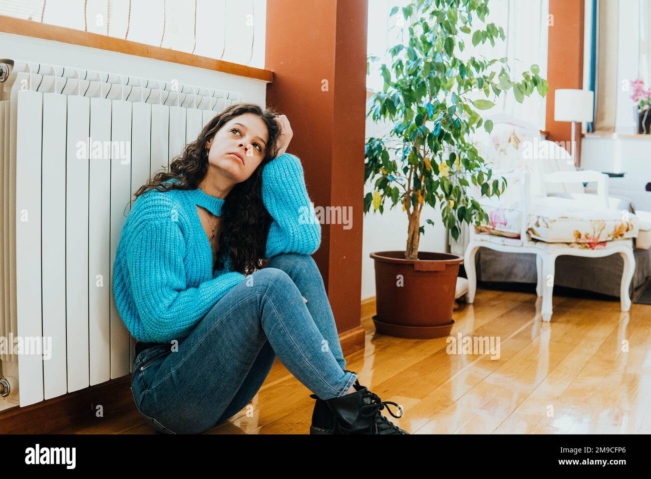 sad woman dressed in blue sitting in the living room of her house Stock ...