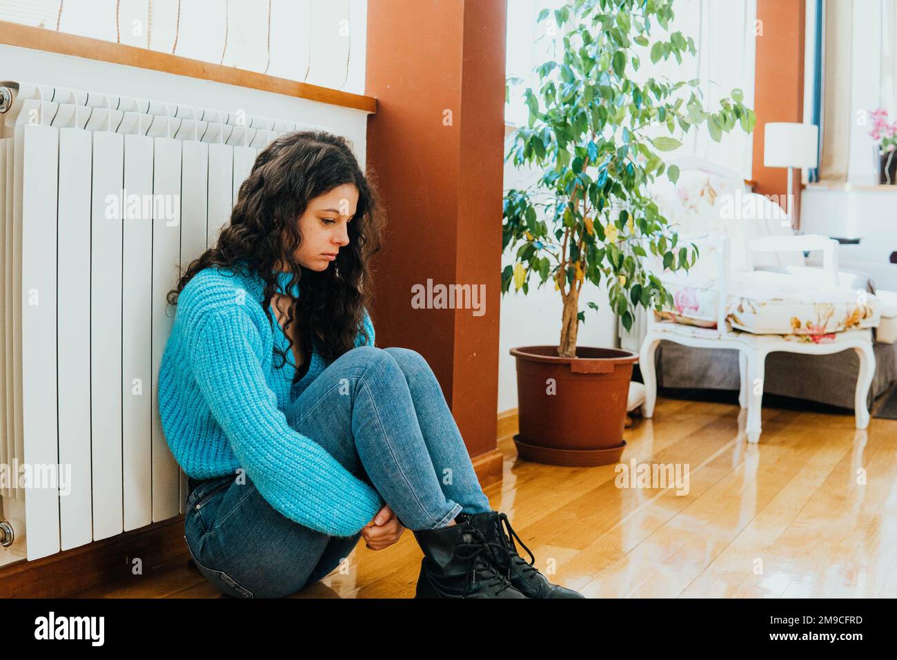 sad woman dressed in blue sitting in the living room of her house Stock ...