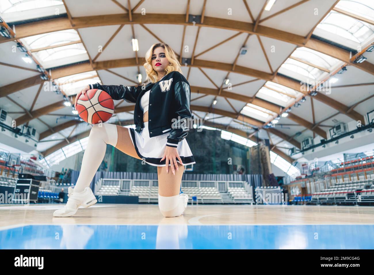 Low Angle Shot Of A Cheerleader Kneeling On One Knee And Holding A