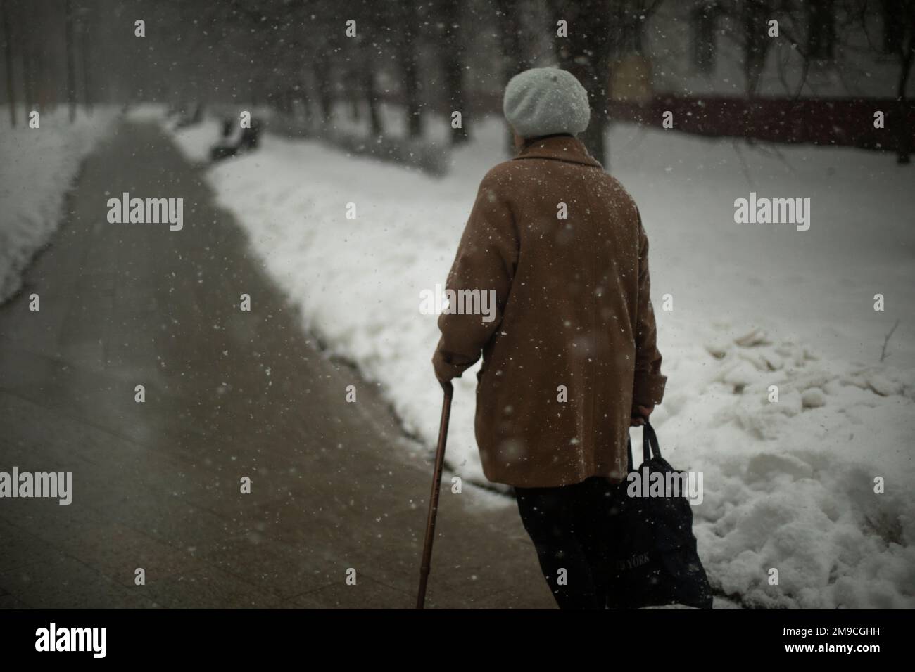 Woman with walking stick. Pensioner walks down road Stock Photo - Alamy