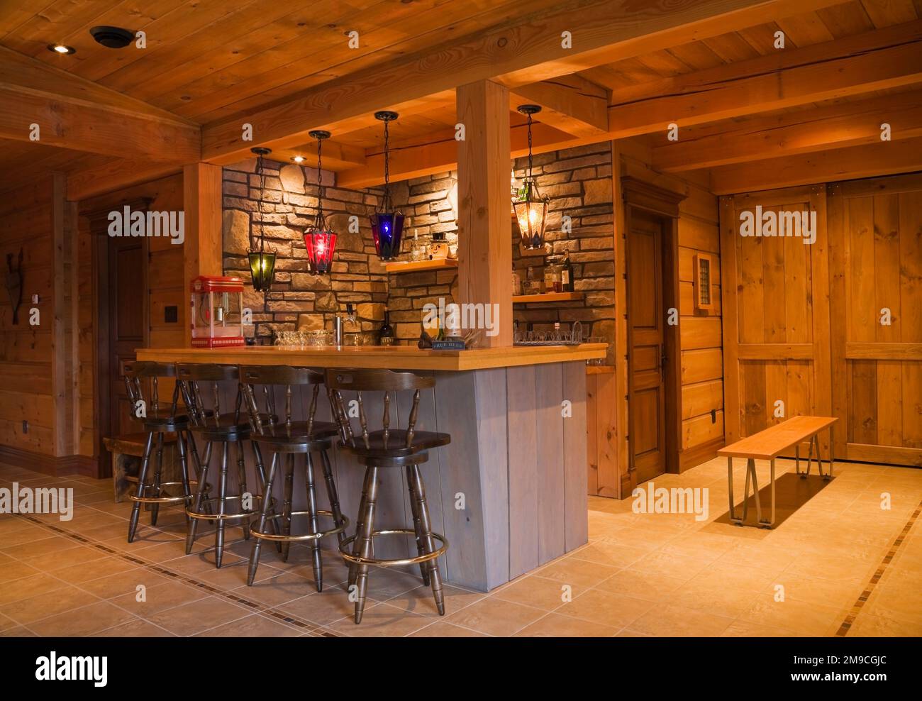 Fully equipped grey wooden bar with antique brown wooden barstools in ...