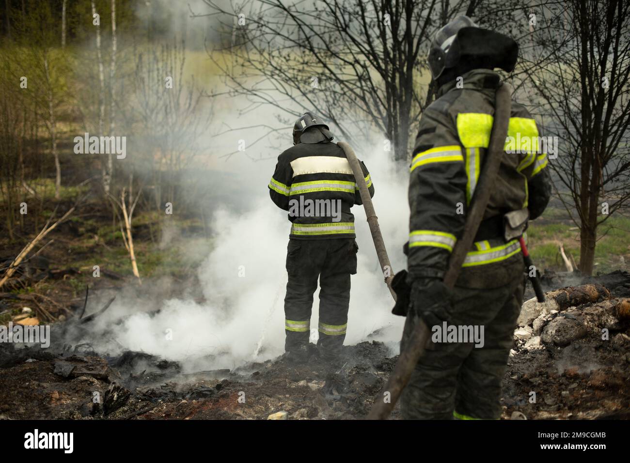 Two firefighters extinguish fire with water Stock Photo - Alamy