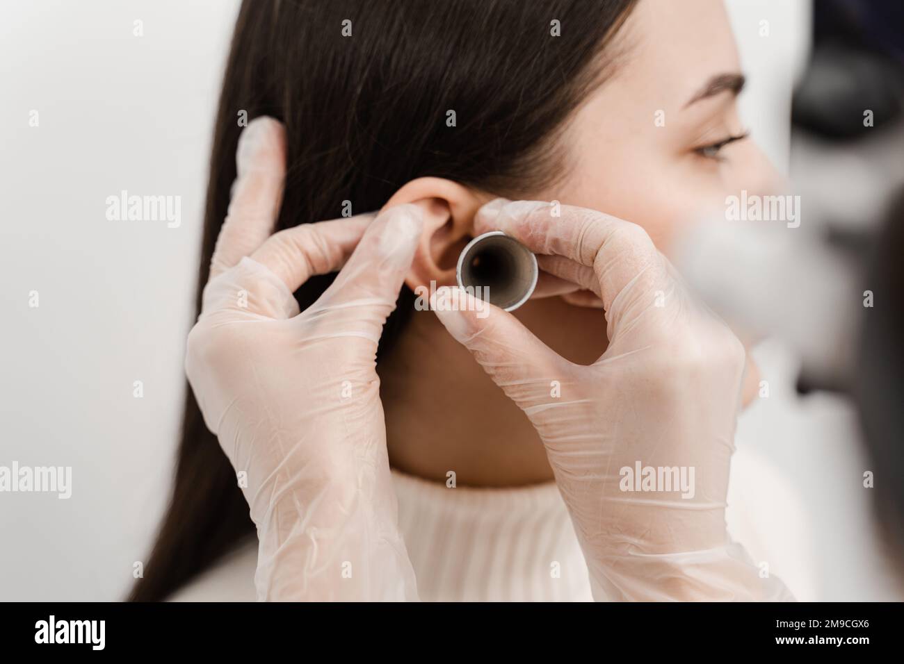Close-up examination of womans ear with ear funnel. Otoscopy. Visit to ...