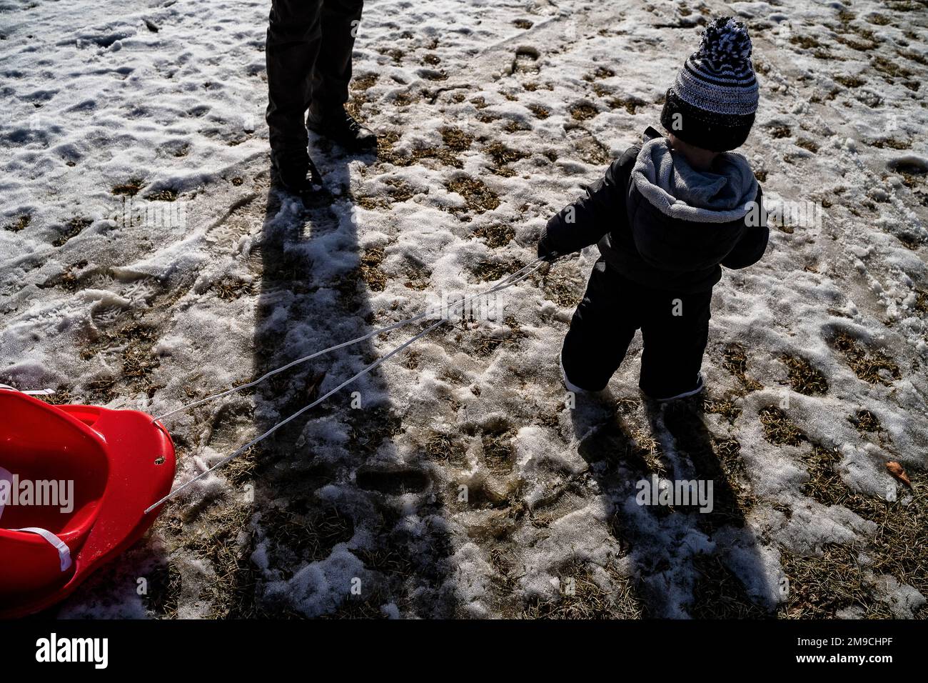 Young Boy Pulling Red Sled on Snowy Ground Stock Photo - Alamy