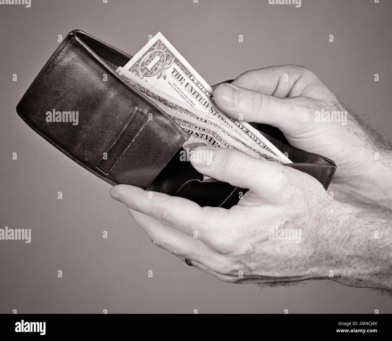 1970s MALE HANDS OPENING A WALLET AND TAKING OUT A ONE DOLLAR $ BILL ...