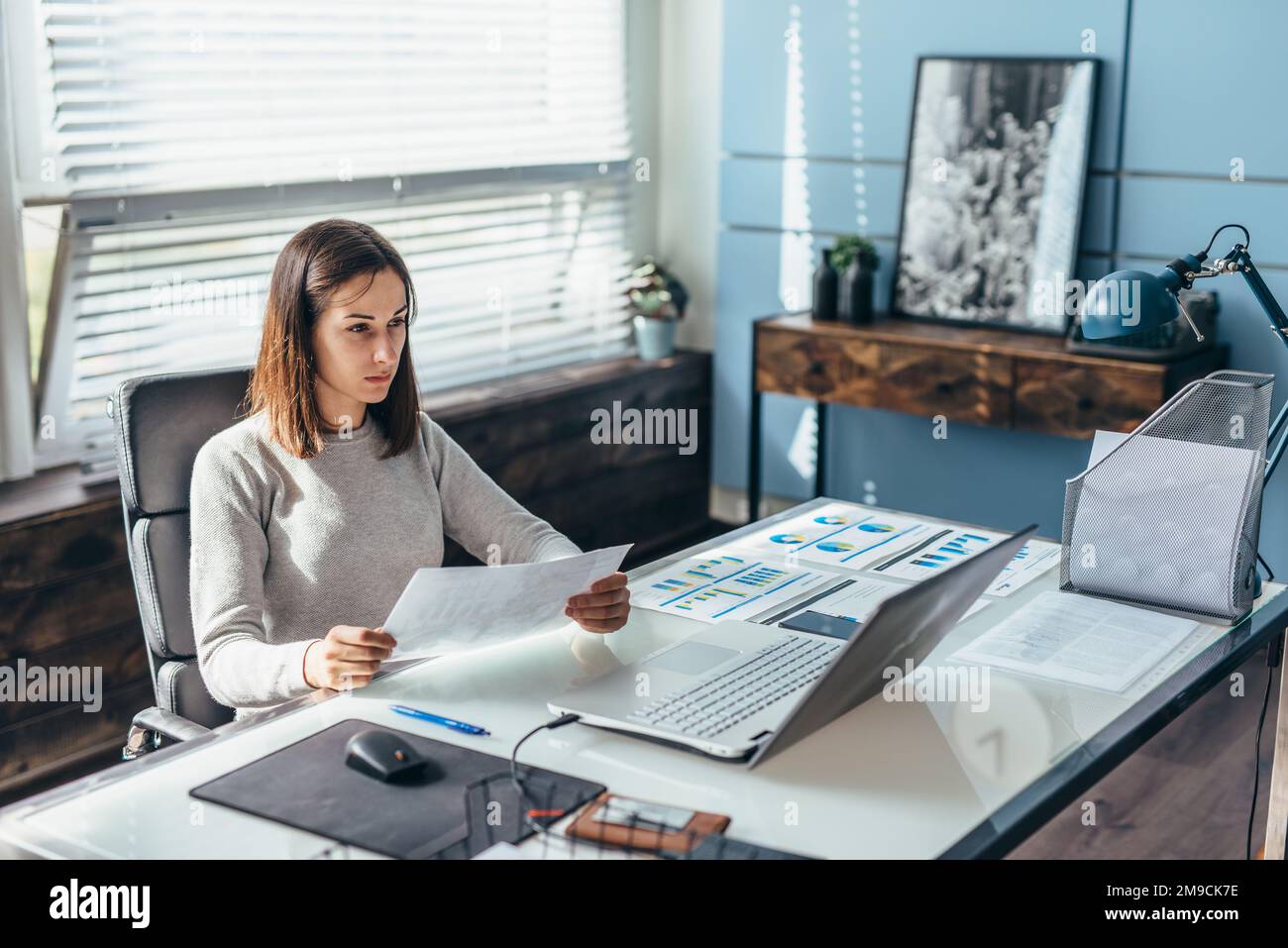 Woman sitting at her desk in the office and working Stock Photo - Alamy