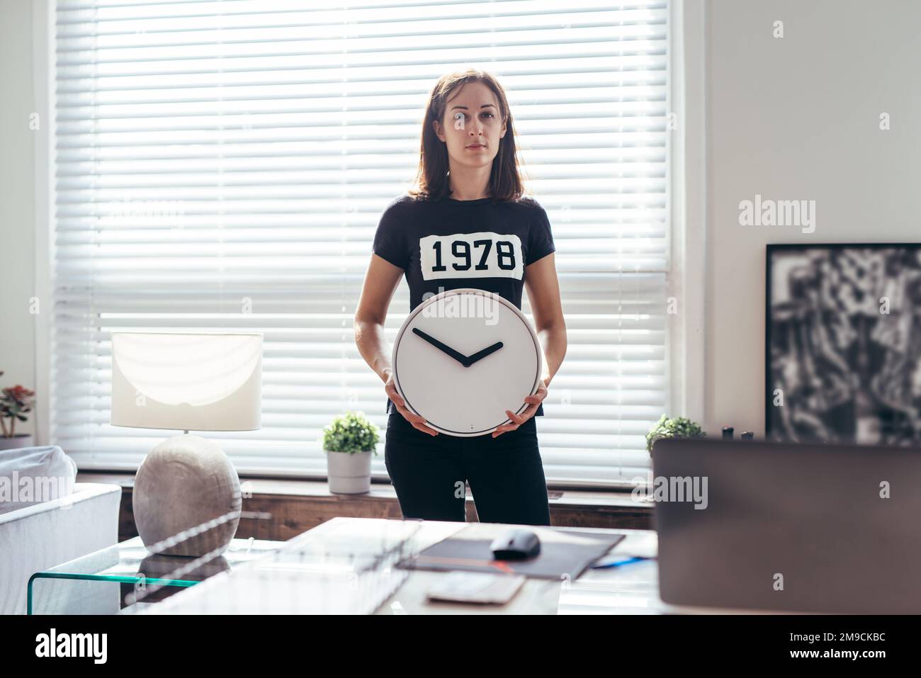 Woman in the workplace holds wall clock Stock Photo - Alamy