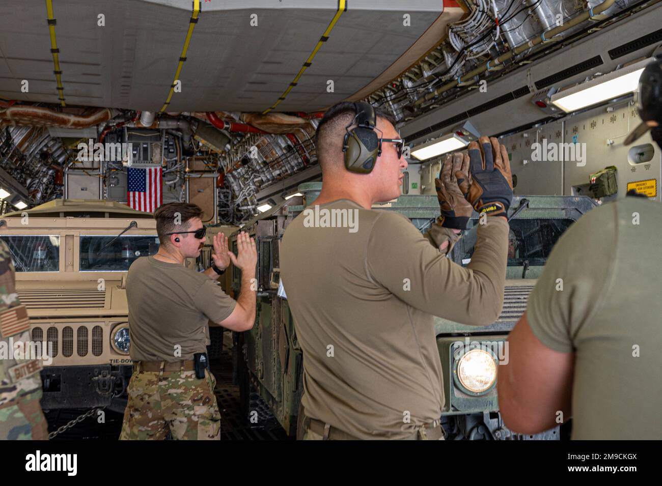 U.S. Airmen guide a High Multipurpose Mobility Wheeled Vehicle onto a C ...