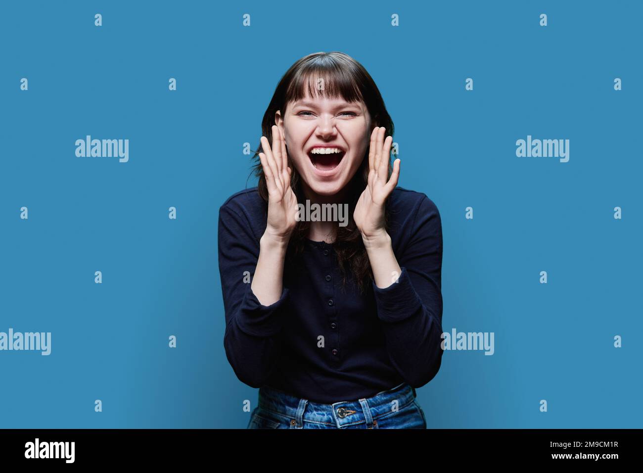 Emotional young female screaming at camera, on blue background Stock ...