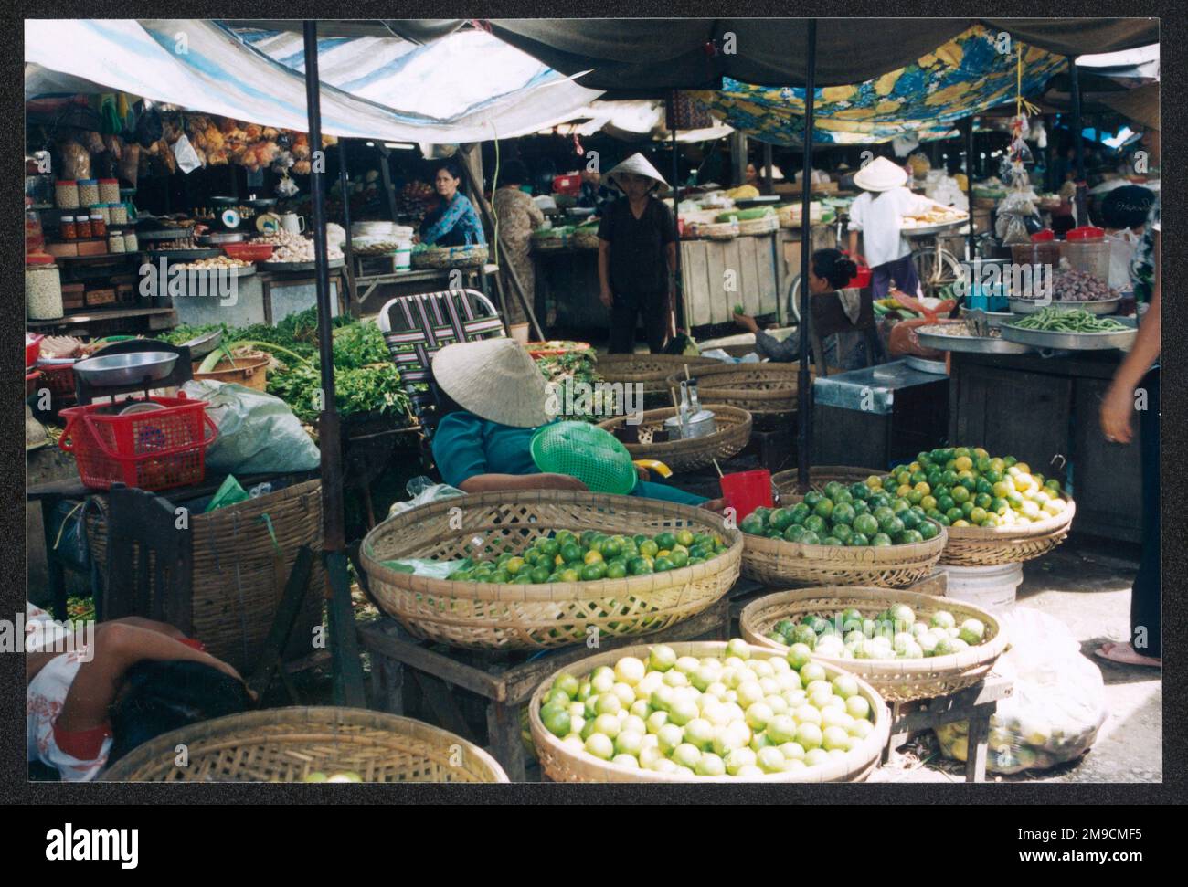 Amidst a busy Vietnamese market scene, one stall holder takes a nap ...