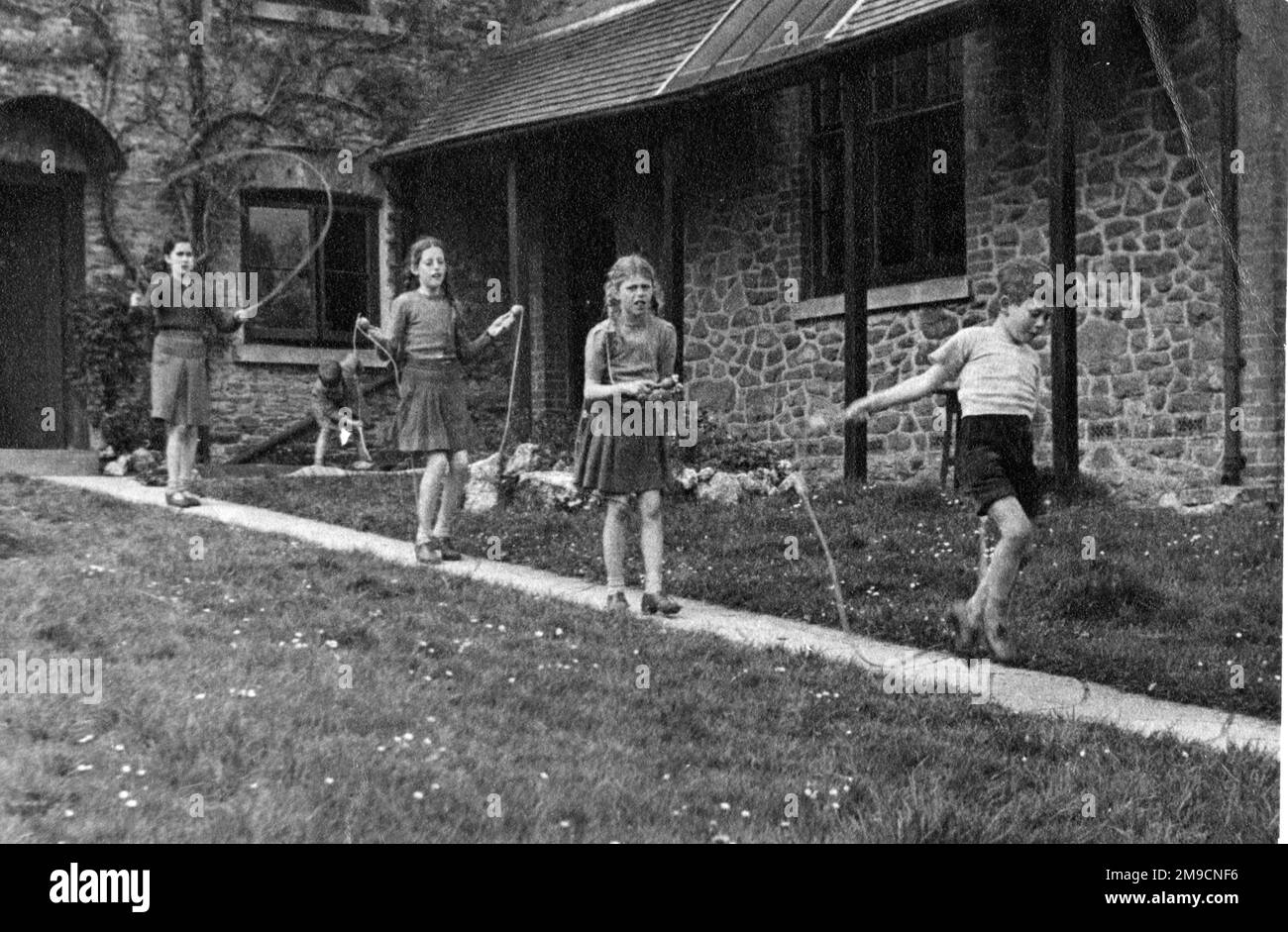 Four girls skipping down a path in Somerset Stock Photo - Alamy