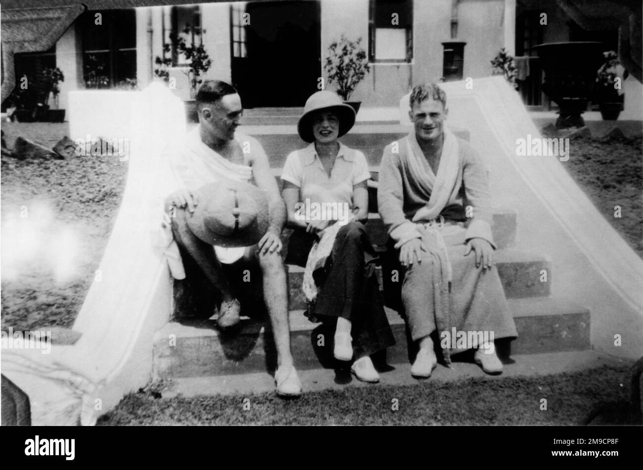 Friends sitting on the steps leading up toward a grand colonial villa ...