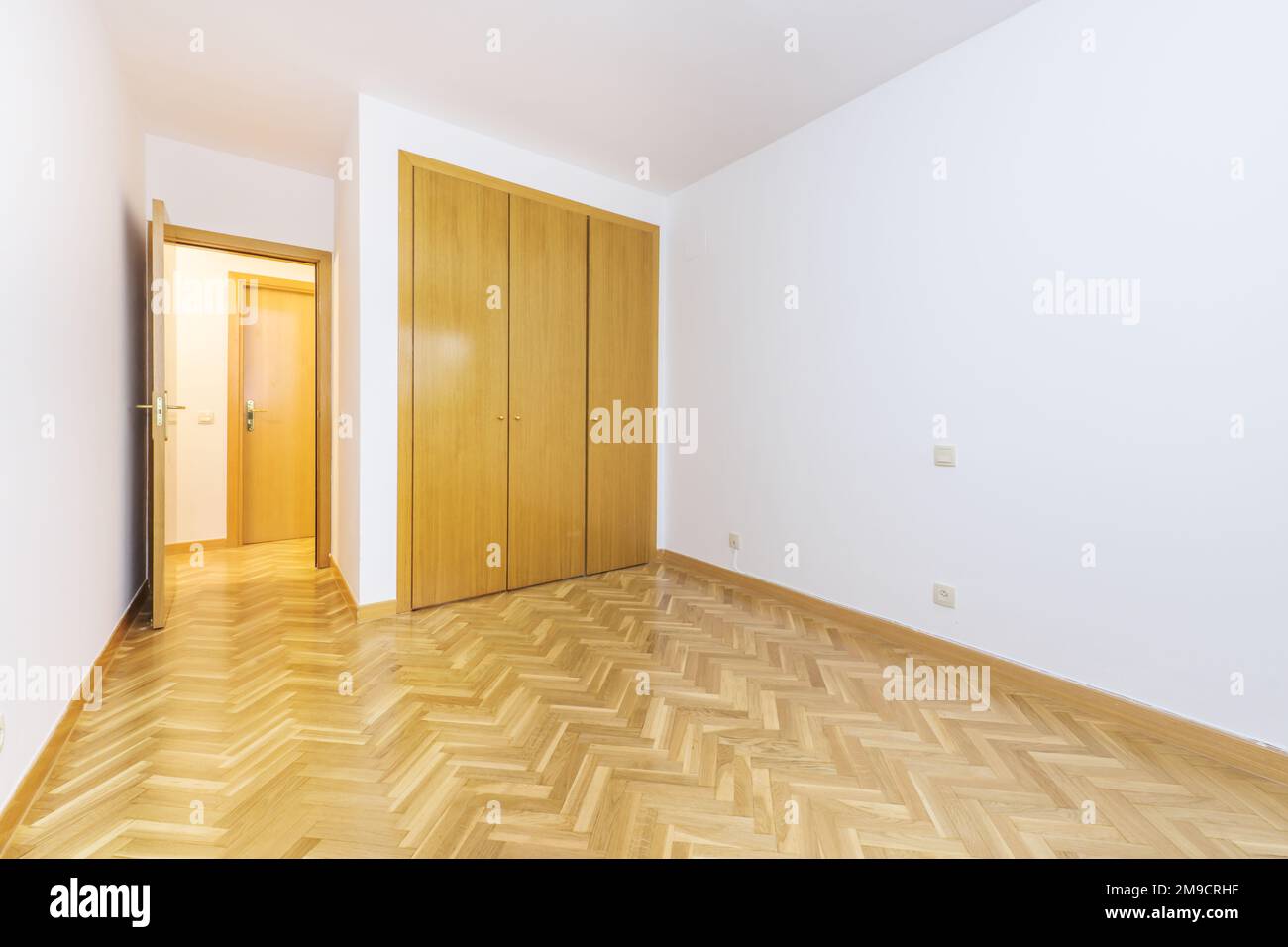 Empty bedroom with a built-in wardrobe with three oak doors and a ...