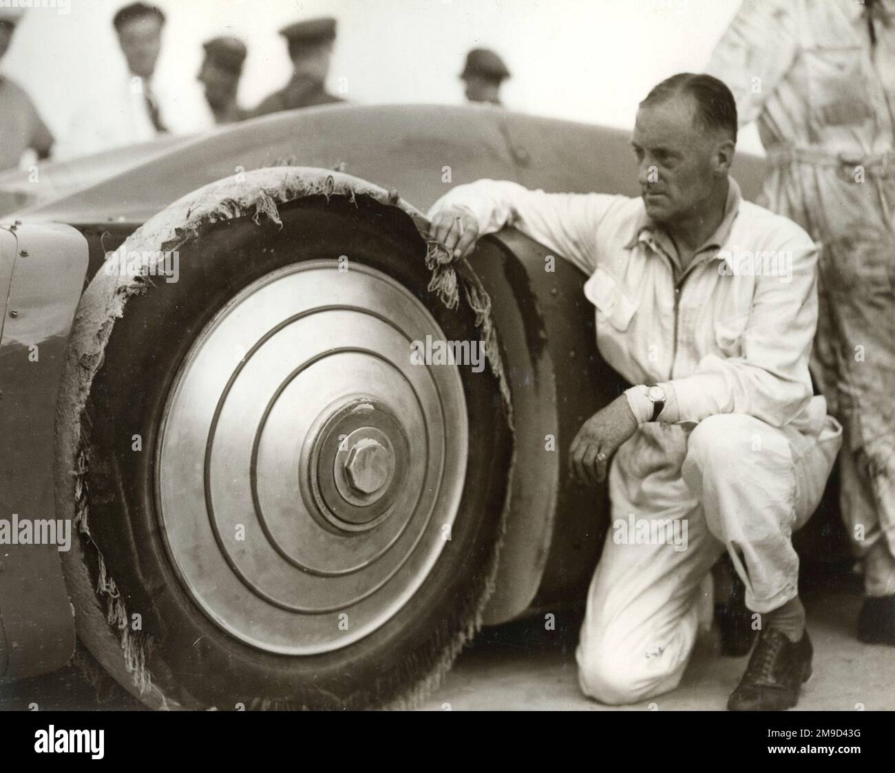 View of Malcolm Campbell kneeling by side of a shredded tyre with ...