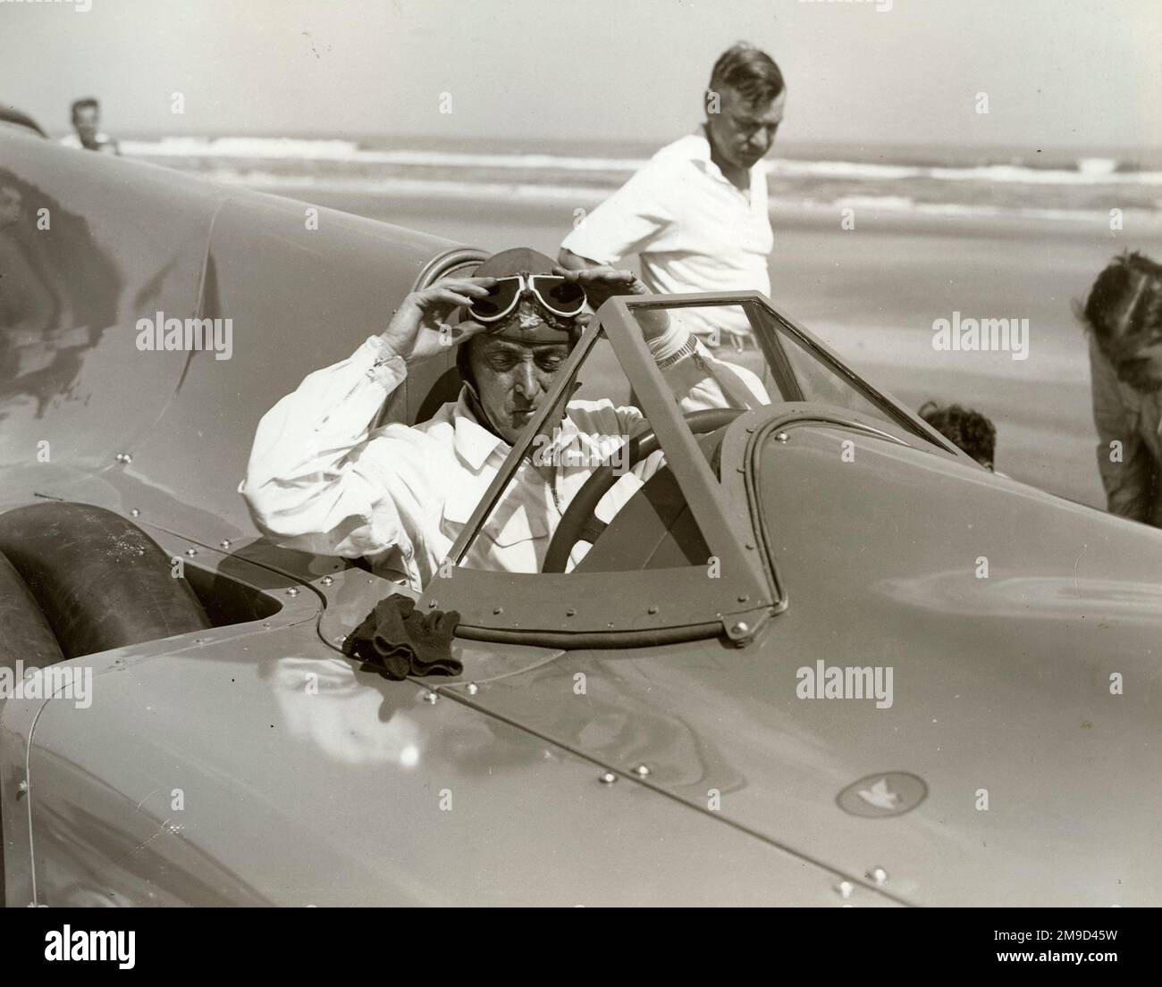 Side view of Campbell in Blue Bird cockpit just putting his goggles on ...