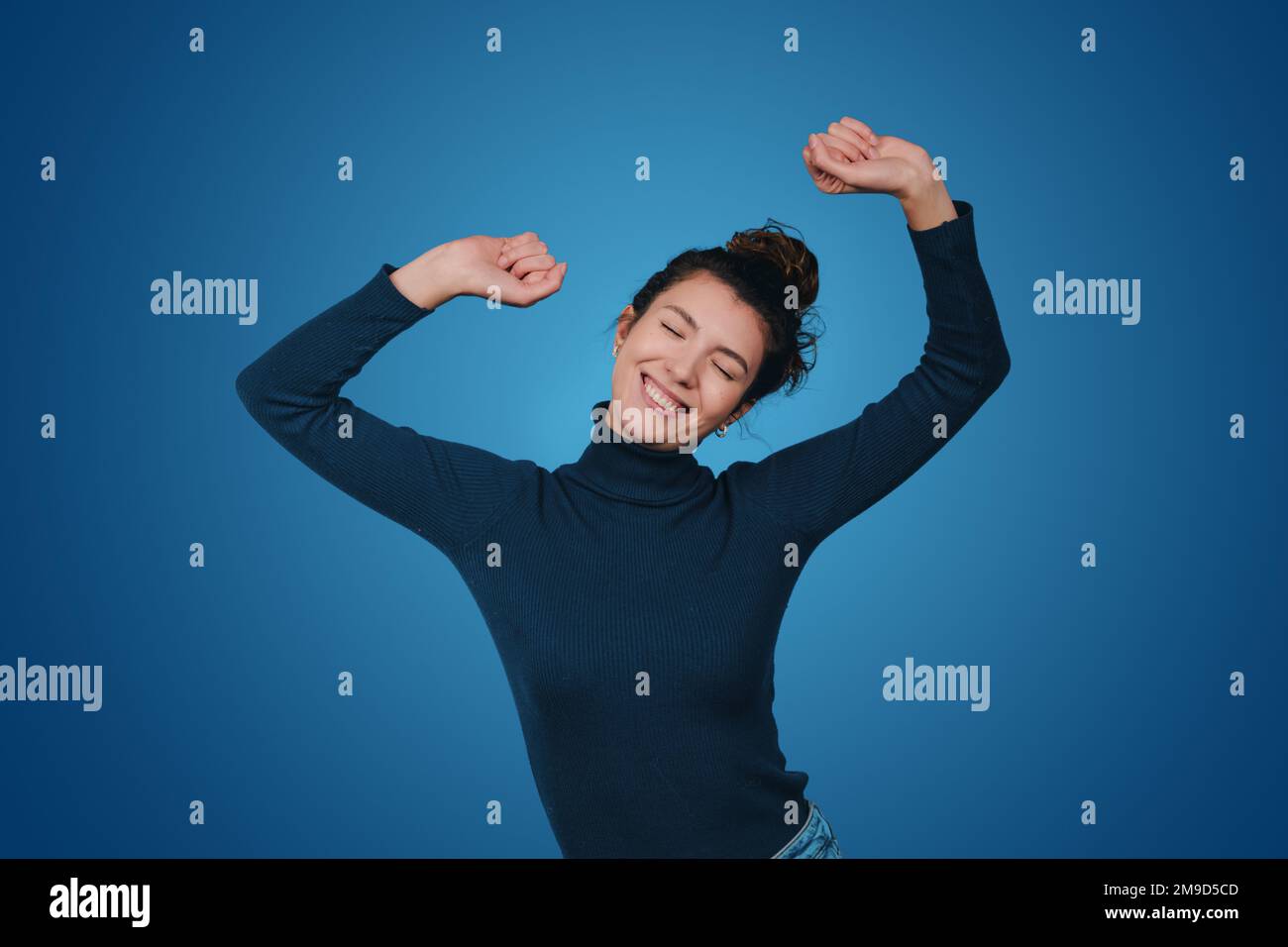 Positive carefree woman raising arms up smiling gladfully keeping eyes ...