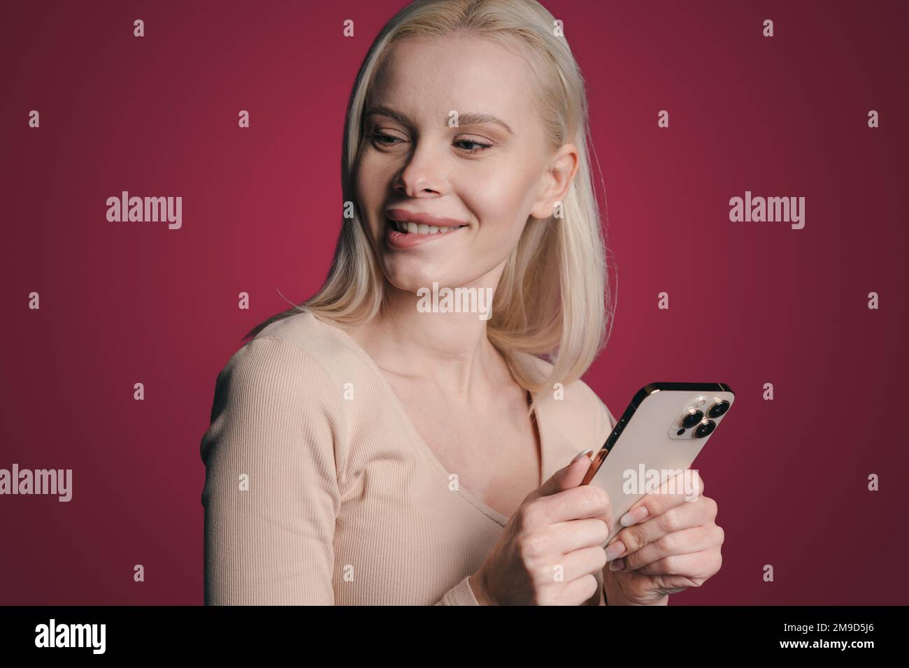 Beautiful happy woman texting on her mobile phone isolated on crimson ...
