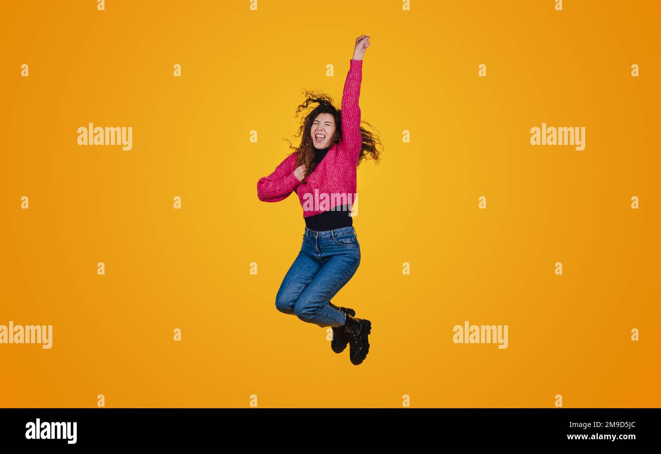 Cheerful funny young woman in casual clothes jumping and spreading ...