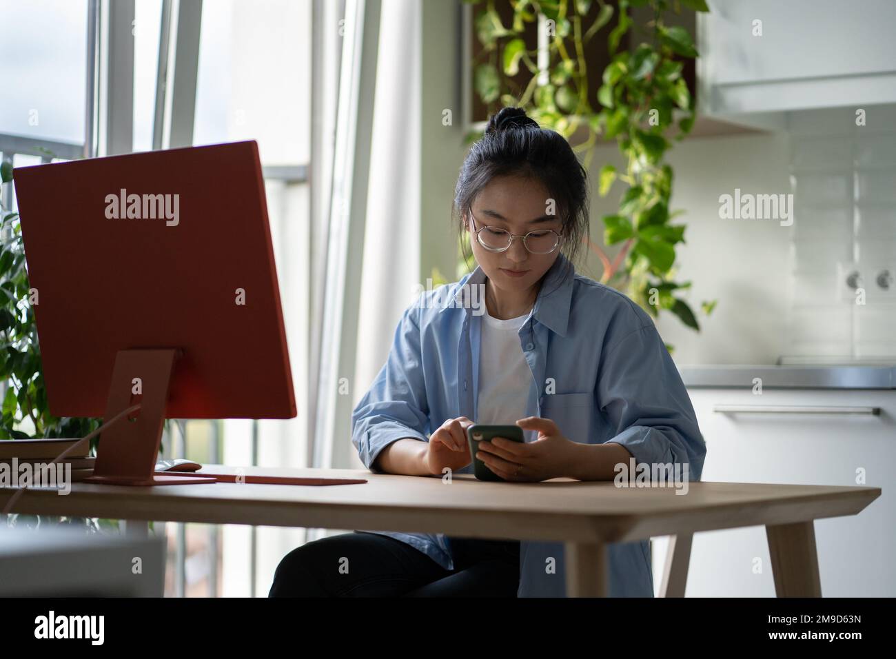 Asian woman remote worker sitting at home office holding smartphone using mobile work tool Stock ...