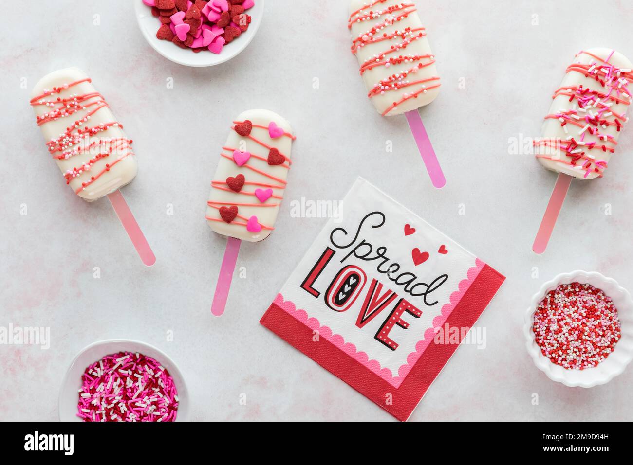 Homemade decorated cakesicles for Valentine's Day with bowls of ...