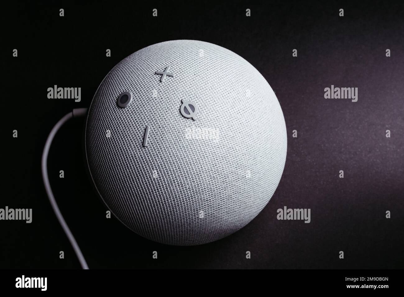 A shot of Amazon Echo 4 with neon blue led light on the bottom part on ...