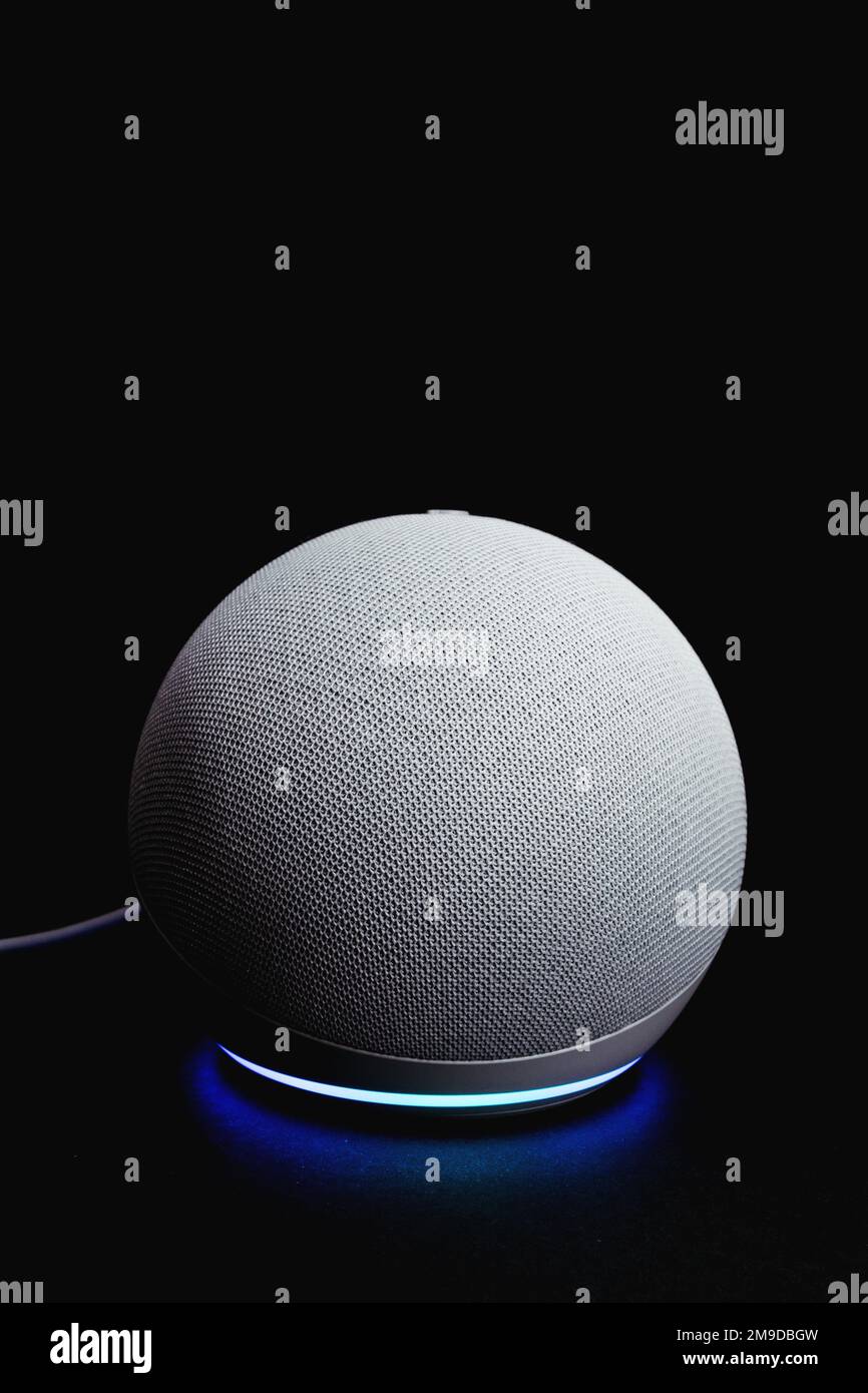 A vertical shot of Amazon Echo 4 with neon blue led light on the bottom part on the black ...