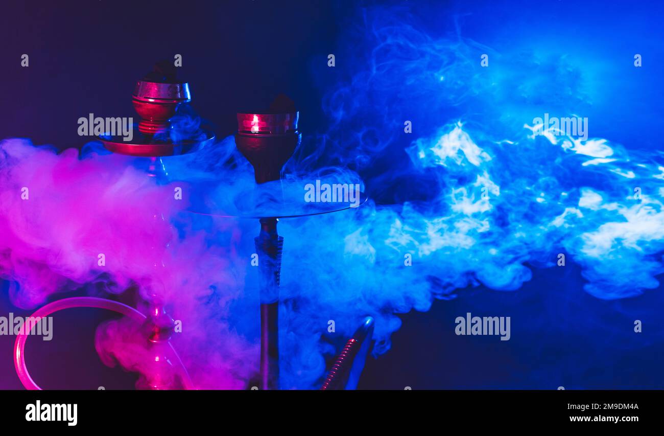 Modern hookah, shisha on smoky black background with colored lighting ...