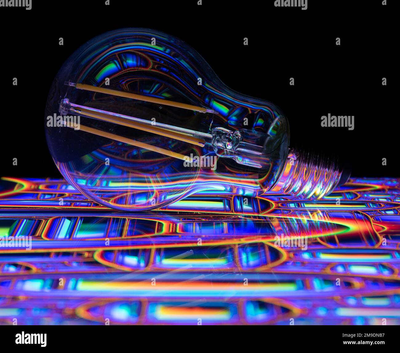 A closeup shot of a light bulb on a colorful illusion background Stock ...