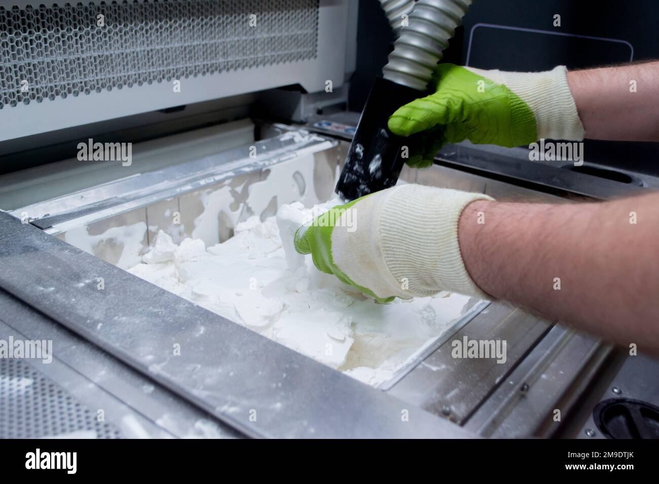 Male worker taking out models from white polyamide powder in working ...