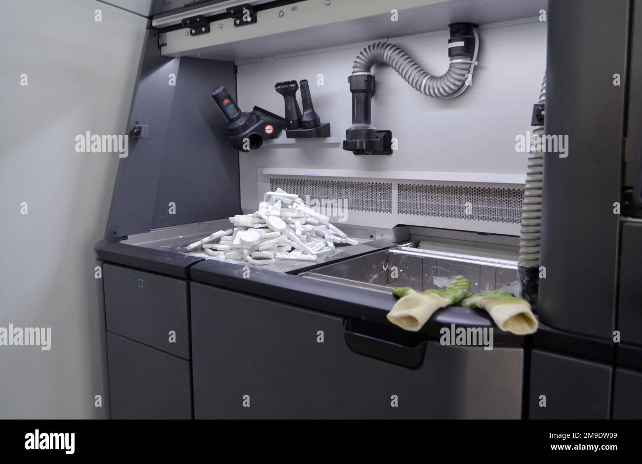 Large powder 3D printer and models printed on it covered with white ...