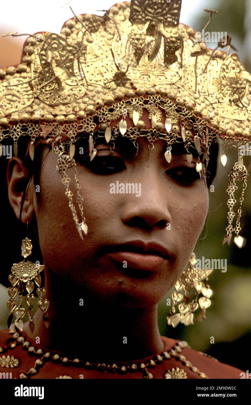 Woman wearing a gold head- dress, costume from Padang in West Sumatra ...