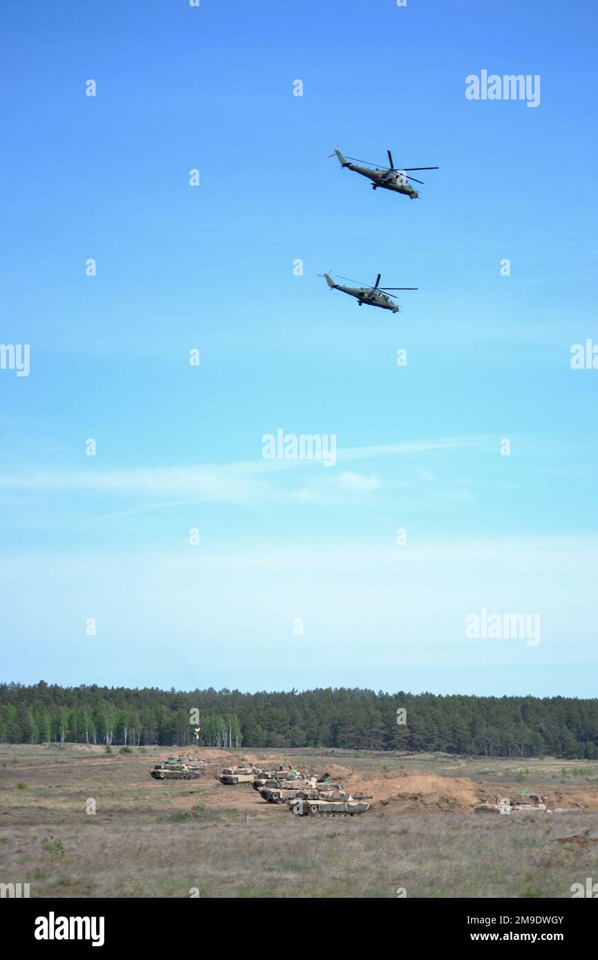Polish Mil Mi-24 attack helicopters fly over U.S. Army M1A2 Abrams ...