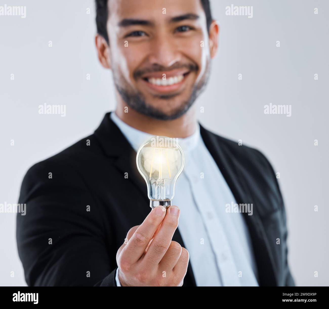.a young man holding a light bulb against a grey background Stock Photo ...