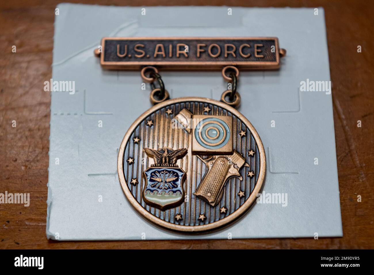 A bronze Excellence-In-Competition pistol badge sits on a table at ...