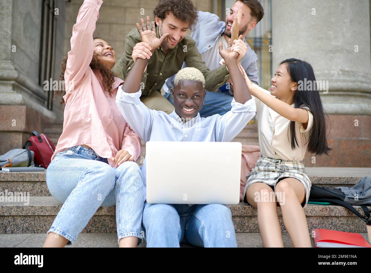 group of students with a laptop giving each other a high five. close-up ...