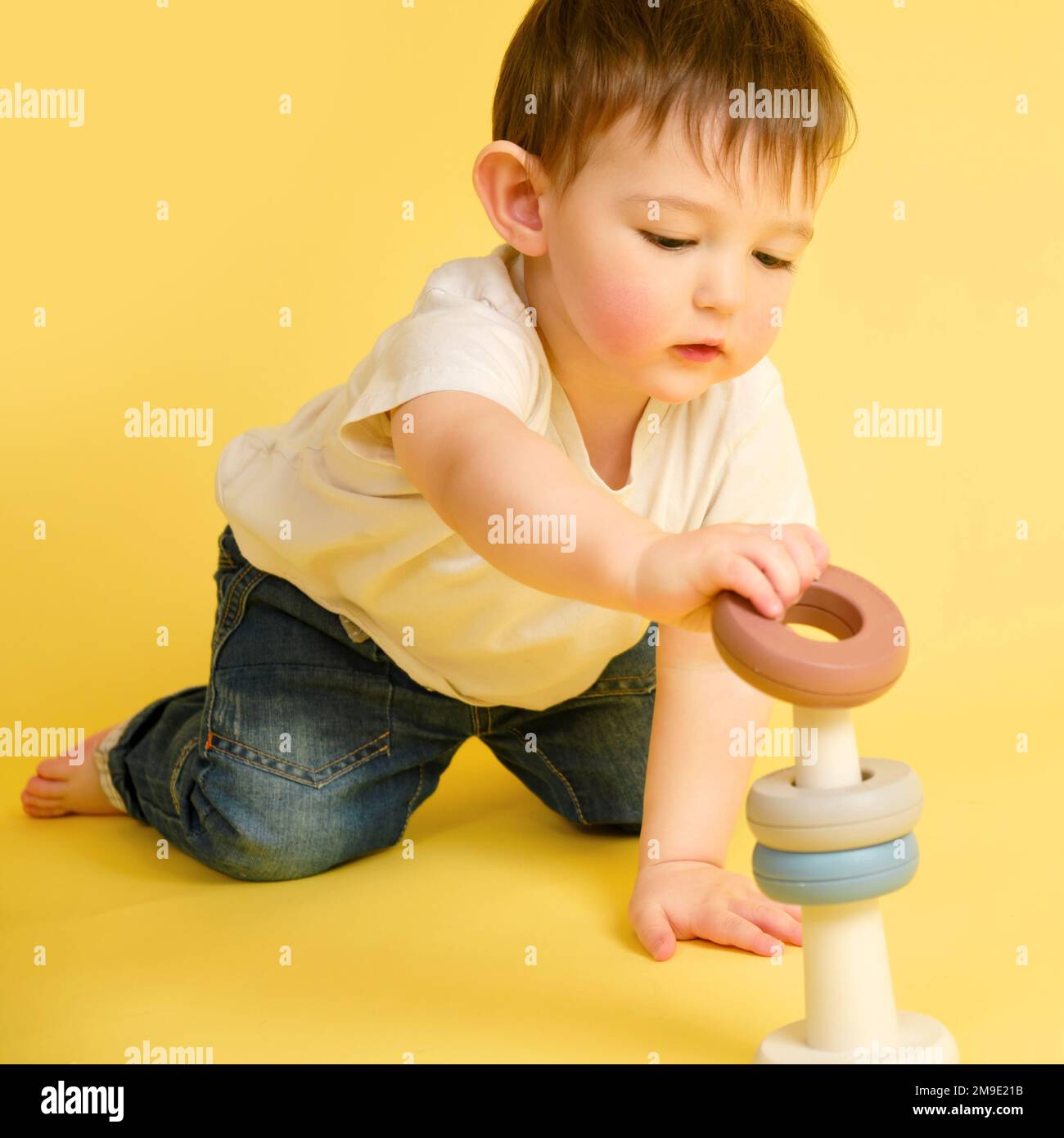 Toddler baby is playing logic educational games with a pyramid on a ...