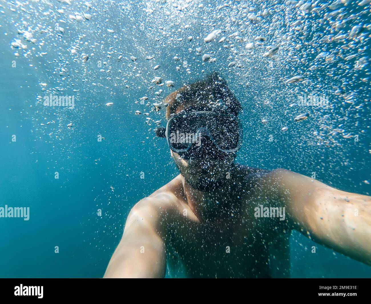 male diver swims in the sea under water with a mask and snorkel is ...