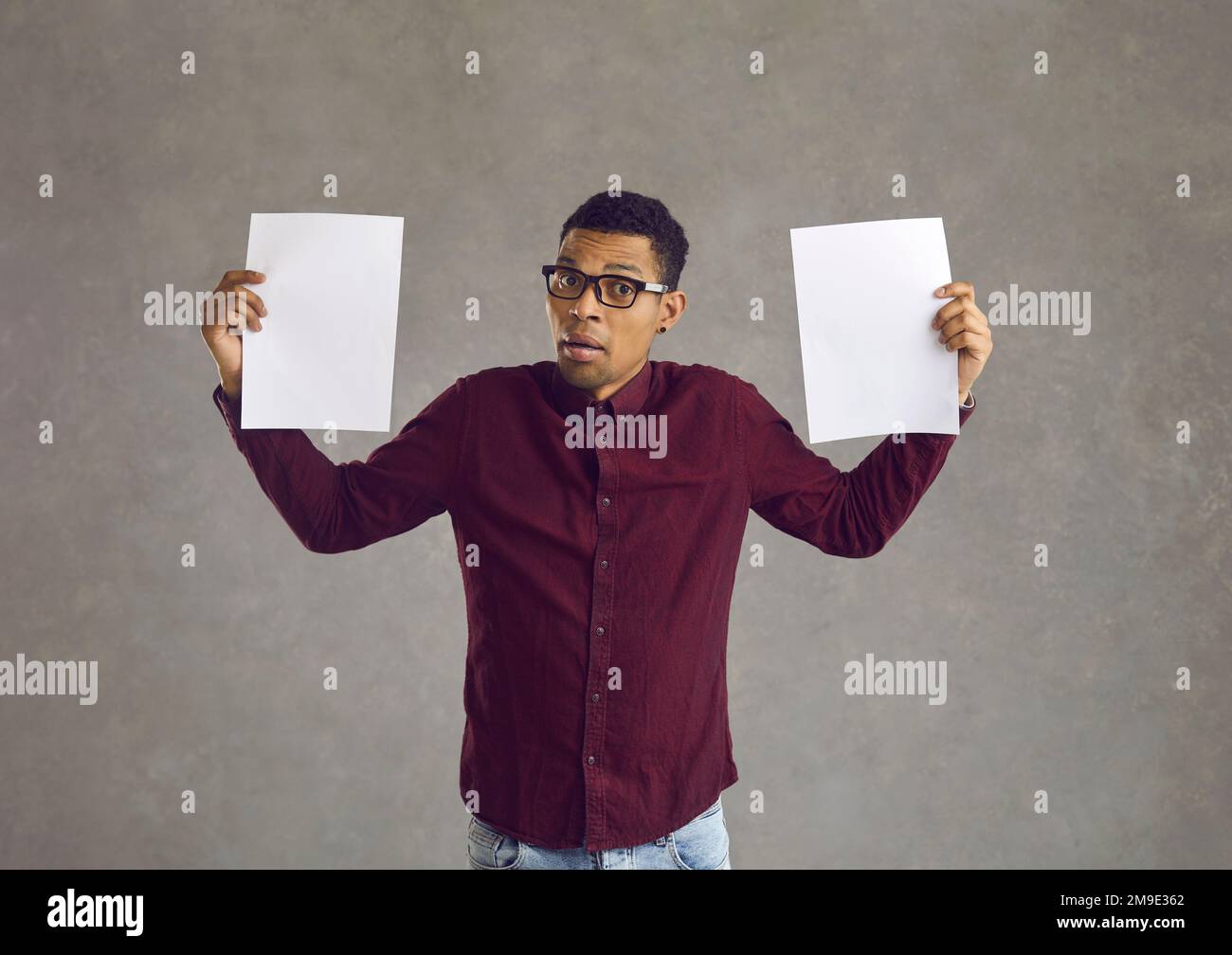 Confused black man holding two blank paper banners and trying to choose ...