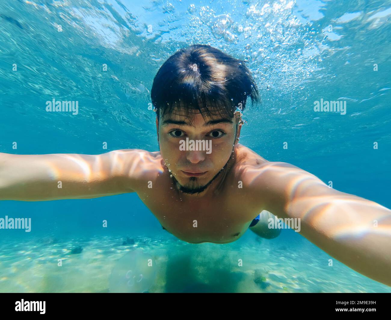 selfie of a man with a funny face swimming under water in the sea at ...