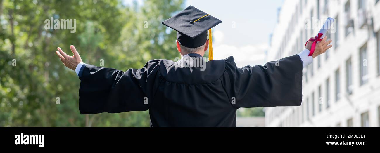 Elderly male graduate rejoices at graduation outdoors. Rear view of a ...