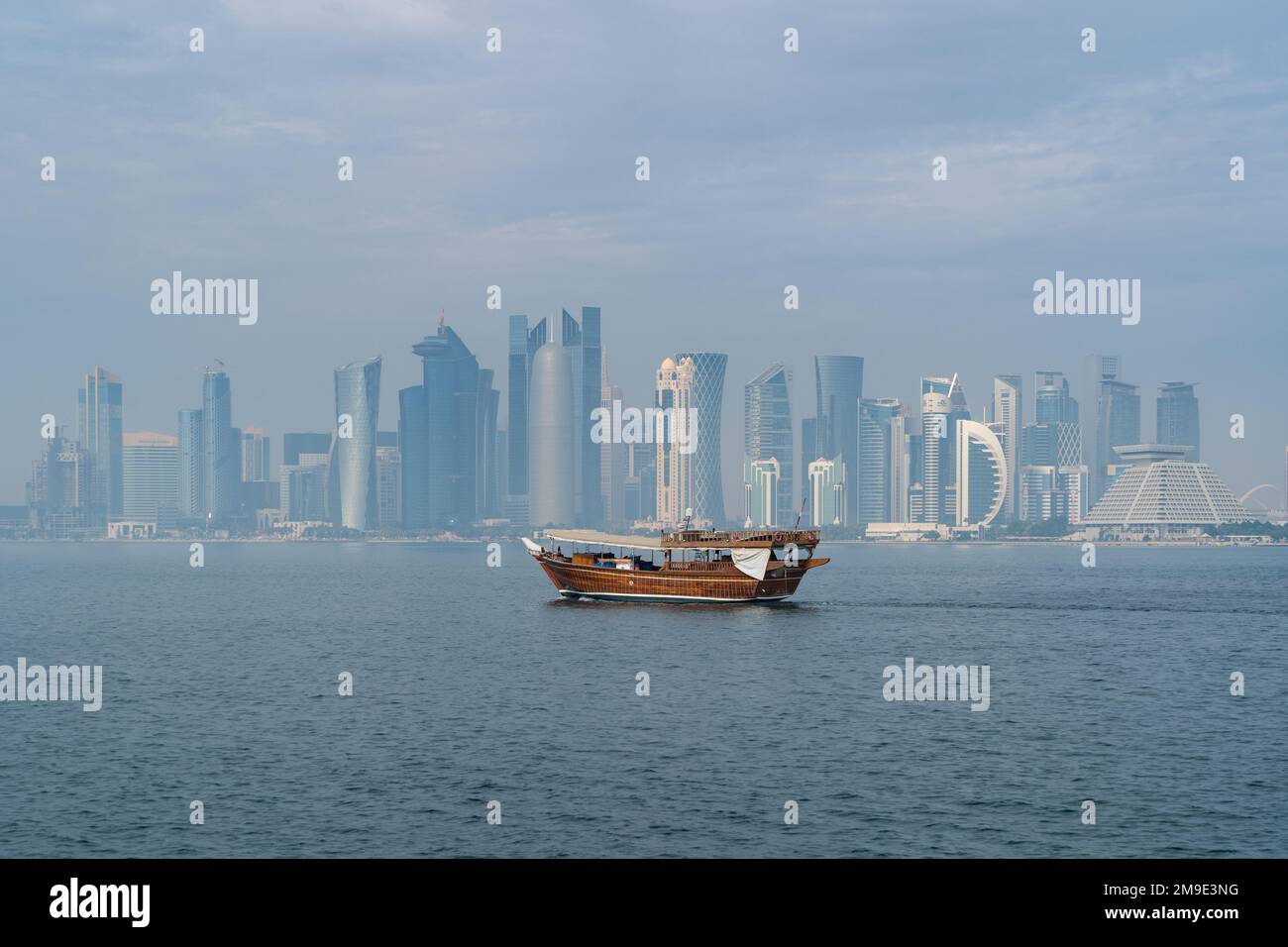 A traditional dhow in Doha, Qatar with the city's modern skyline in the ...