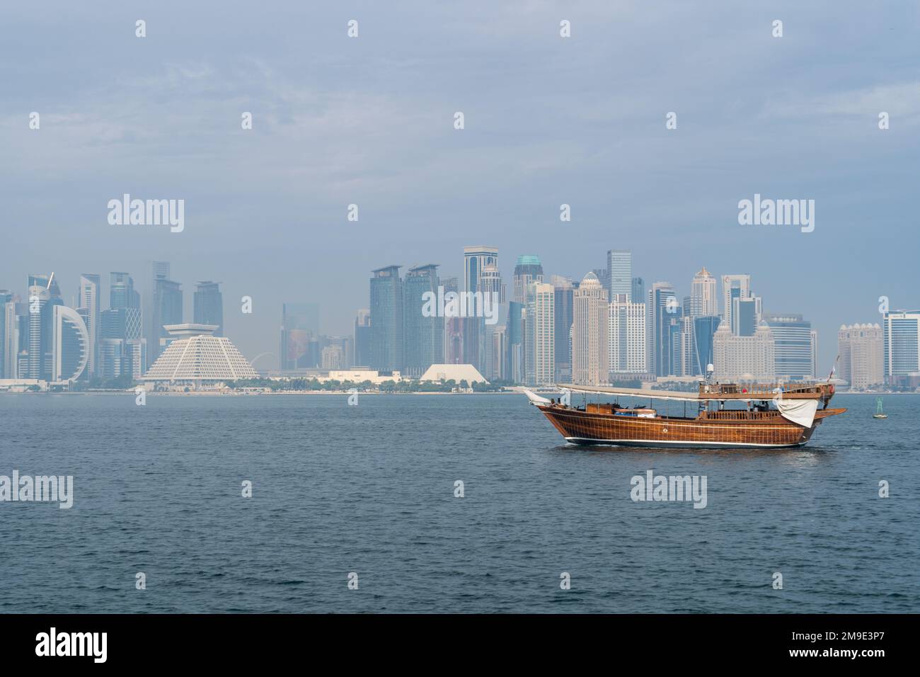 A traditional dhow in Doha, Qatar with the city's modern skyline in the ...