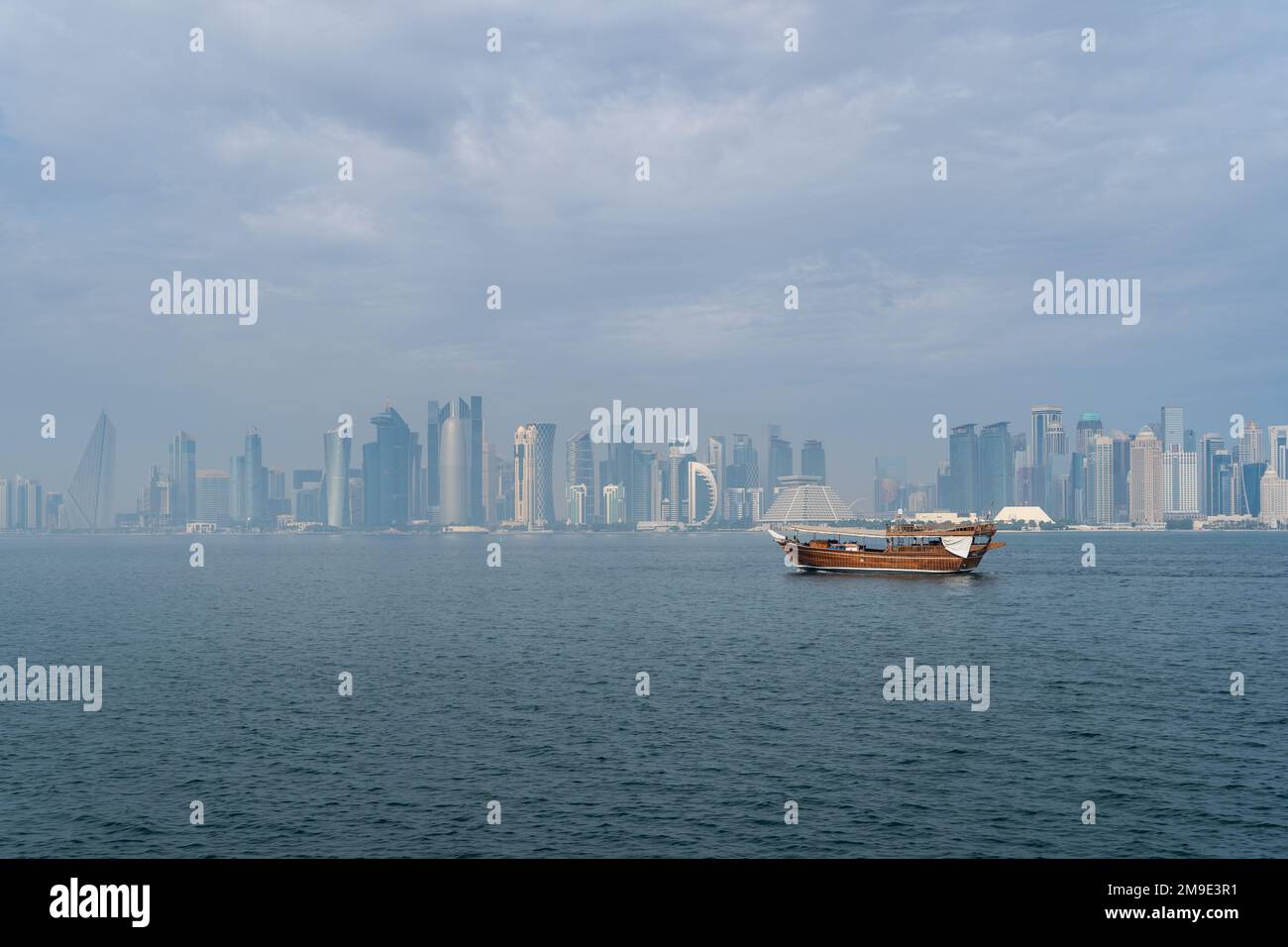 A traditional dhow in Doha, Qatar with the city's modern skyline in the ...
