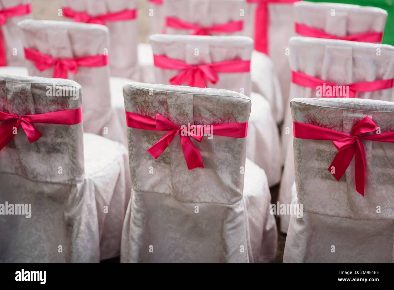 chairs for wedding ceremony decorated with white fabric and pink ...